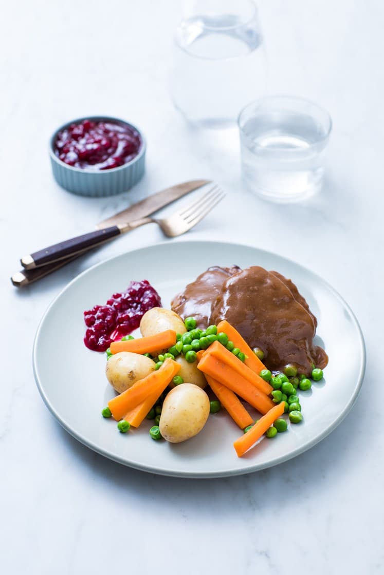 Grove karbonader i brun saus med poteter, erter og rørte tyttebær ...